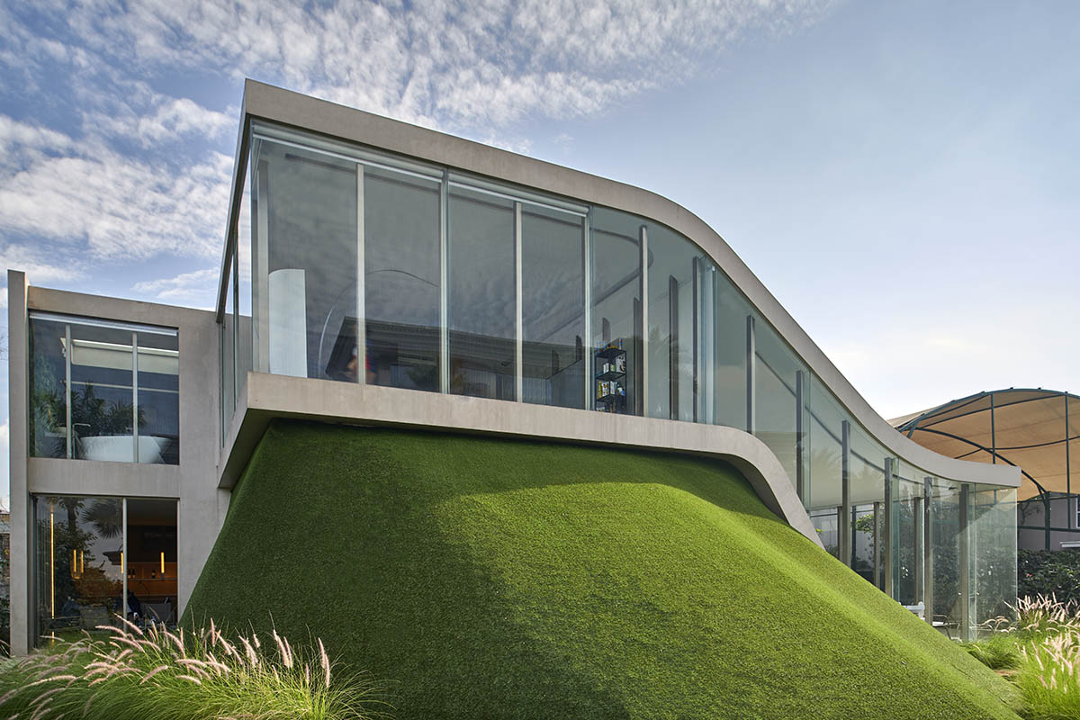 Undulating residence by RDMA is placed onto grass covered earth mound ...