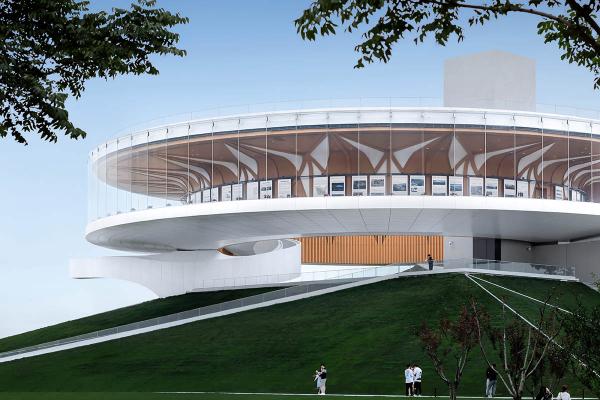 STUDIO A+ designs climbable ring-shaped art center on a green mound in ...